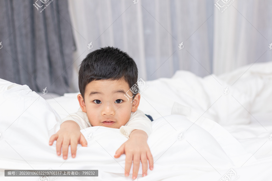 一个小男孩趴在舒适的床上摄影素材汇图网